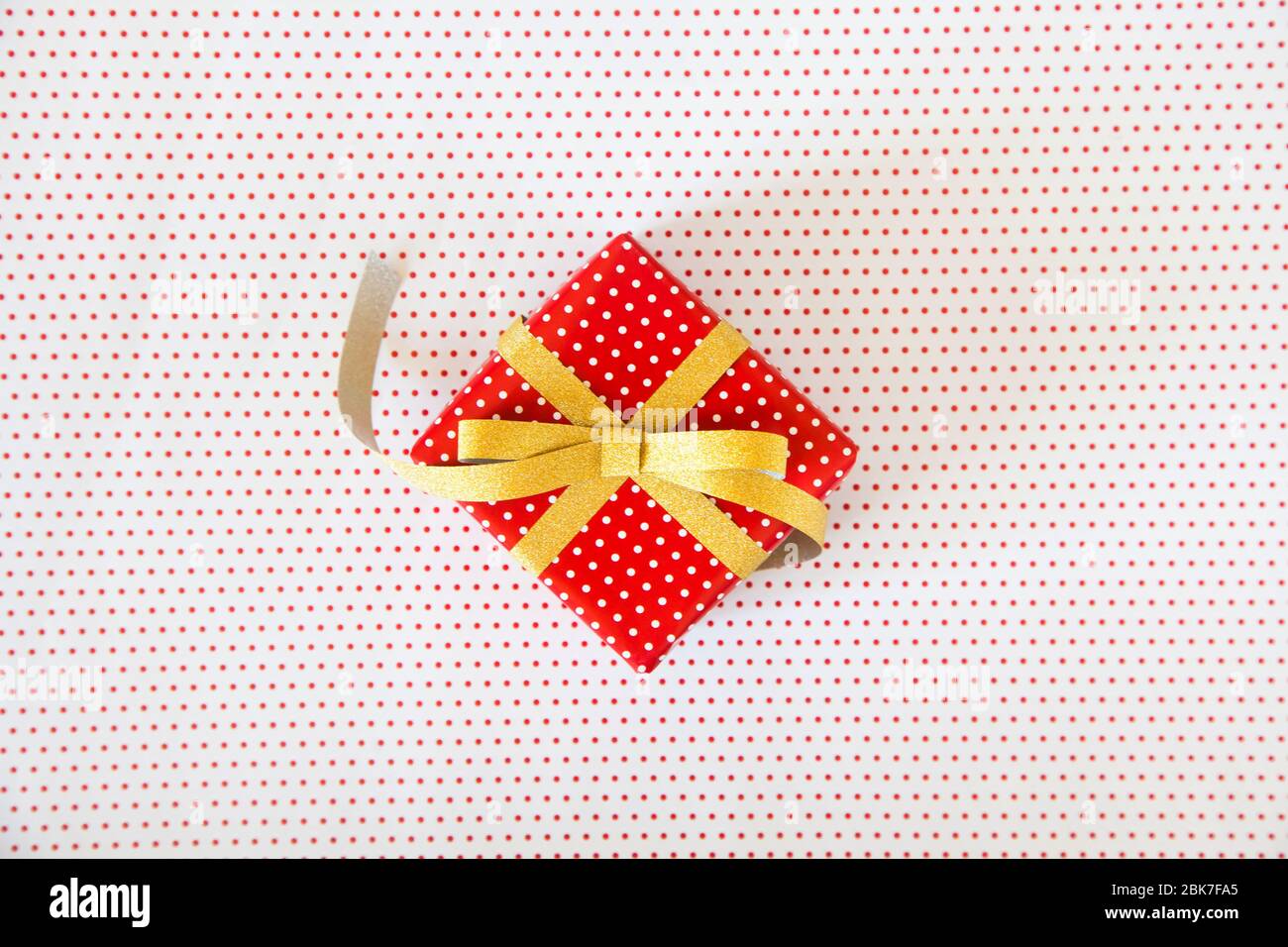 Red gift with gold ribbon on the white polka dot background Stock Photo ...