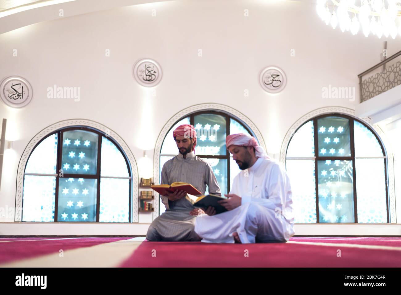 Two muliethnic religious muslim young people praying and reading Koran ...