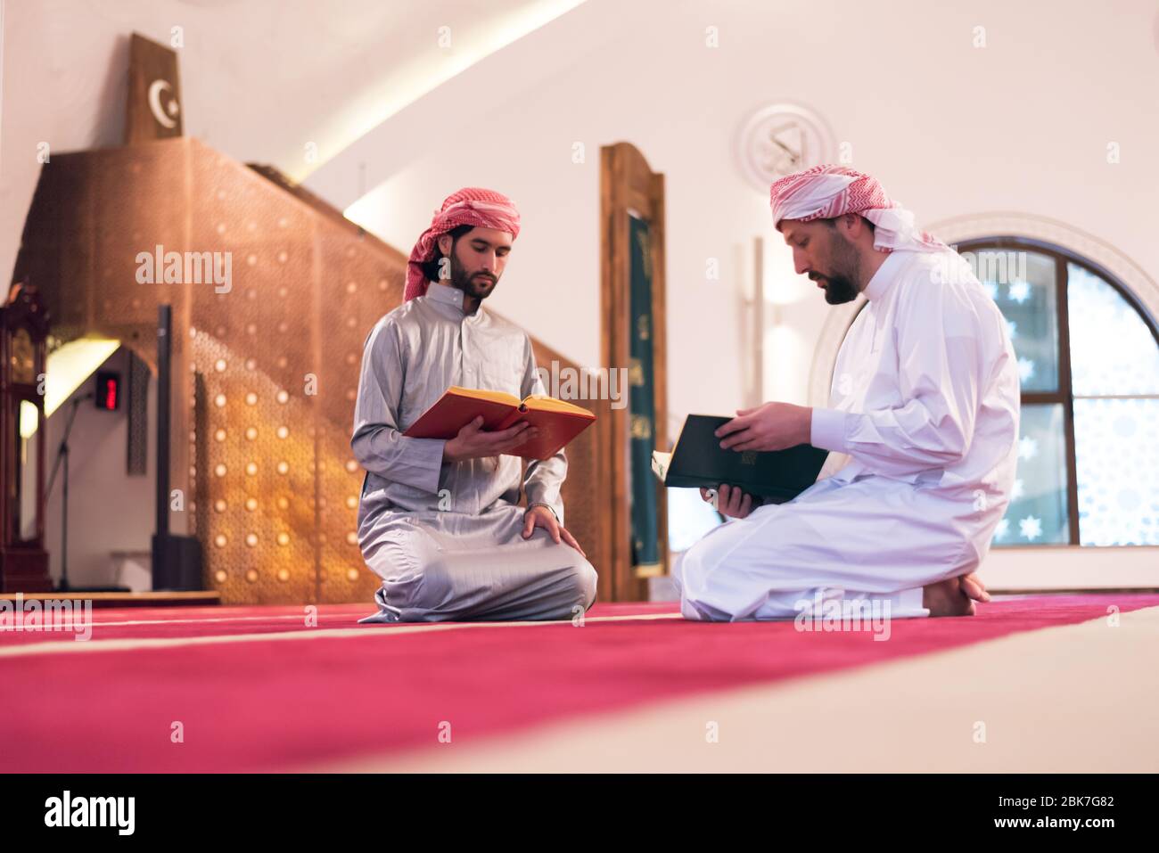 Two muliethnic religious muslim young people praying and reading Koran ...