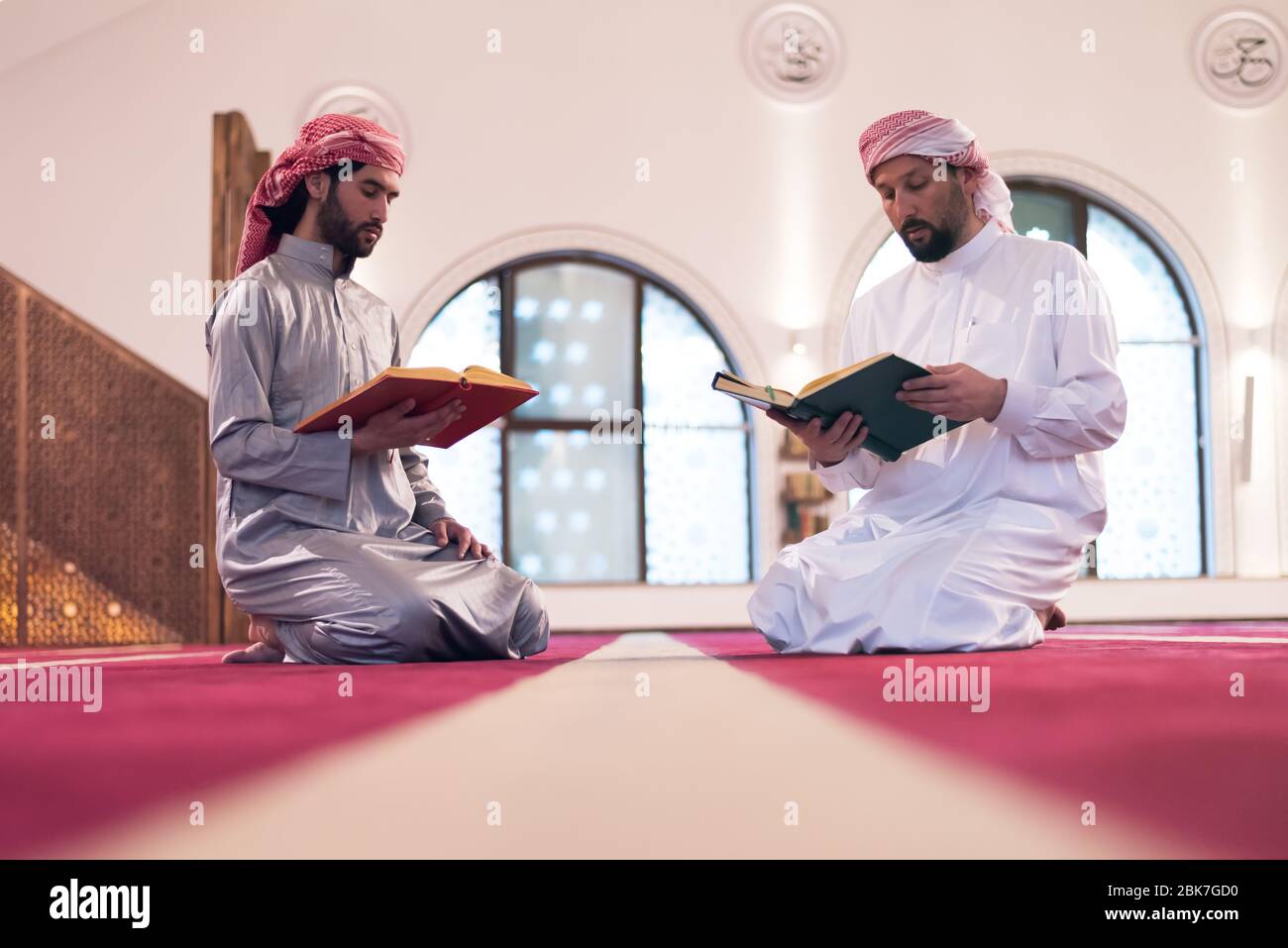 Two muliethnic religious muslim young people praying and reading Koran ...