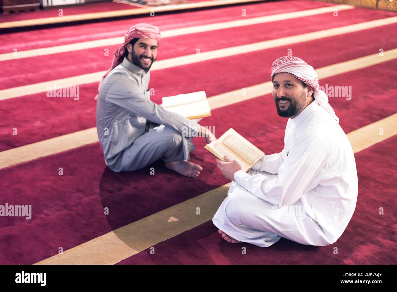 Two muliethnic religious muslim young people praying and reading Koran ...