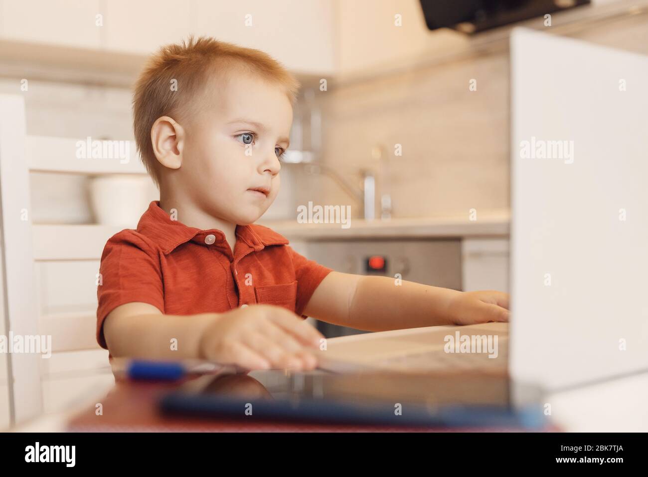 Boy child enthusiastically watching video blog or cartoons on laptop ...