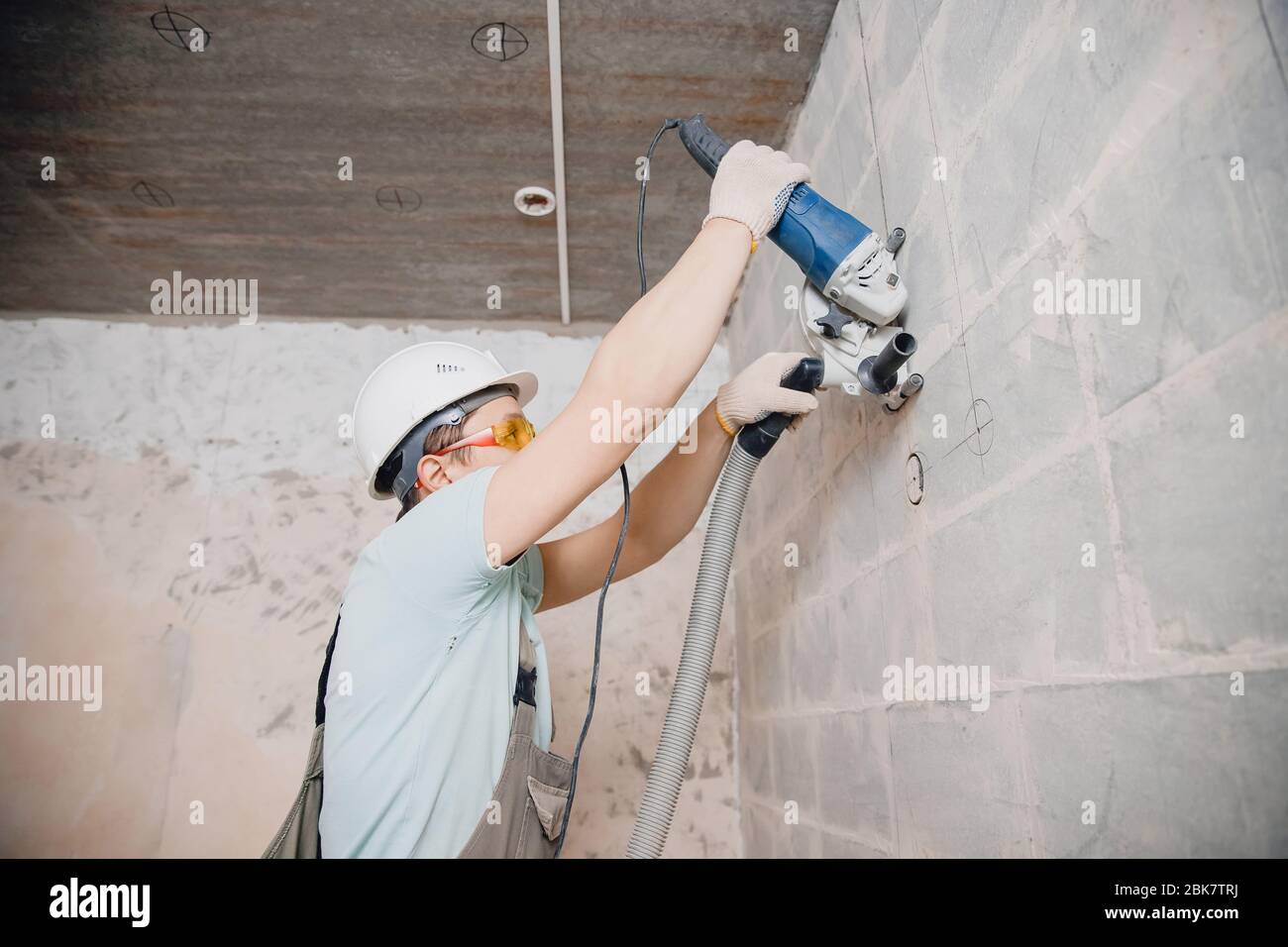 Builder worker cutting electrical chase in concrete wall with ...