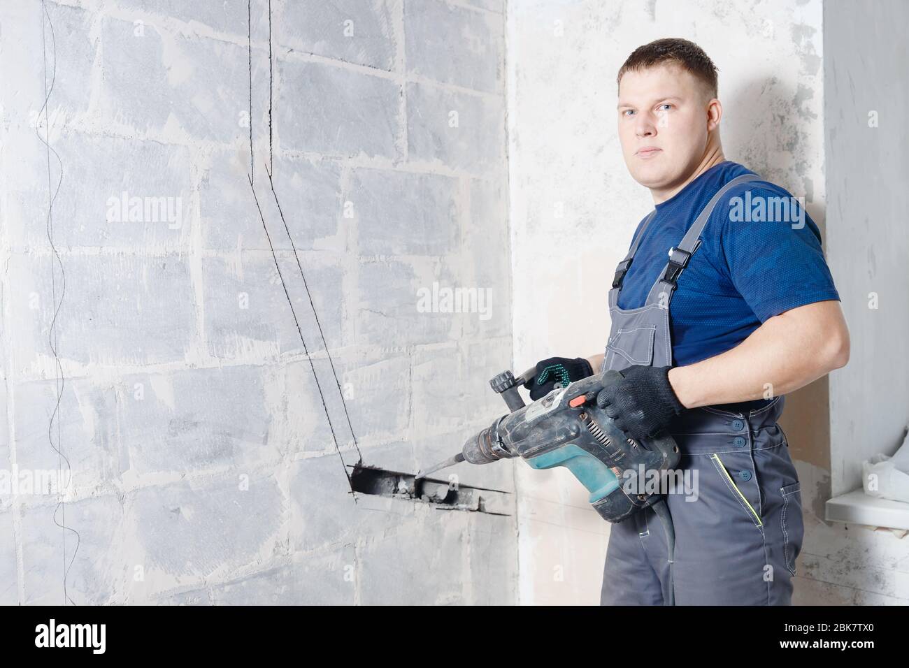 Builder worker man using jackhammer to drill into construction wall for ...