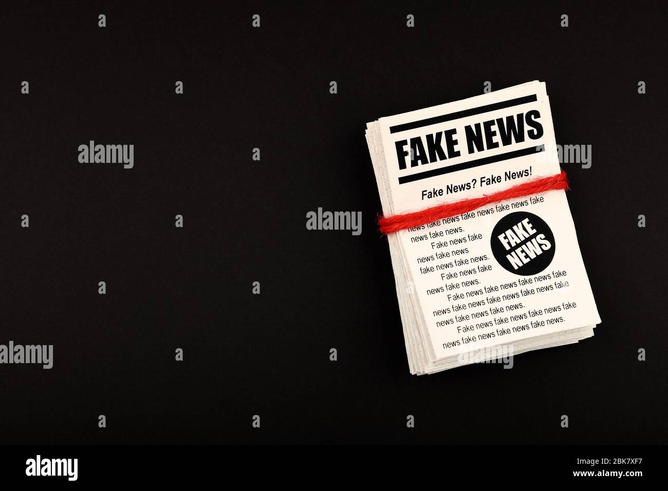 Close up stack of FAKE NEWS newspapers over black paper background with ...