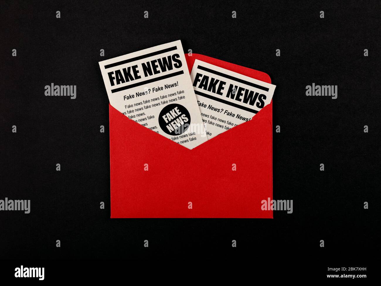 Close up brown paper mail envelope with FAKE NEWS newspapers over black ...