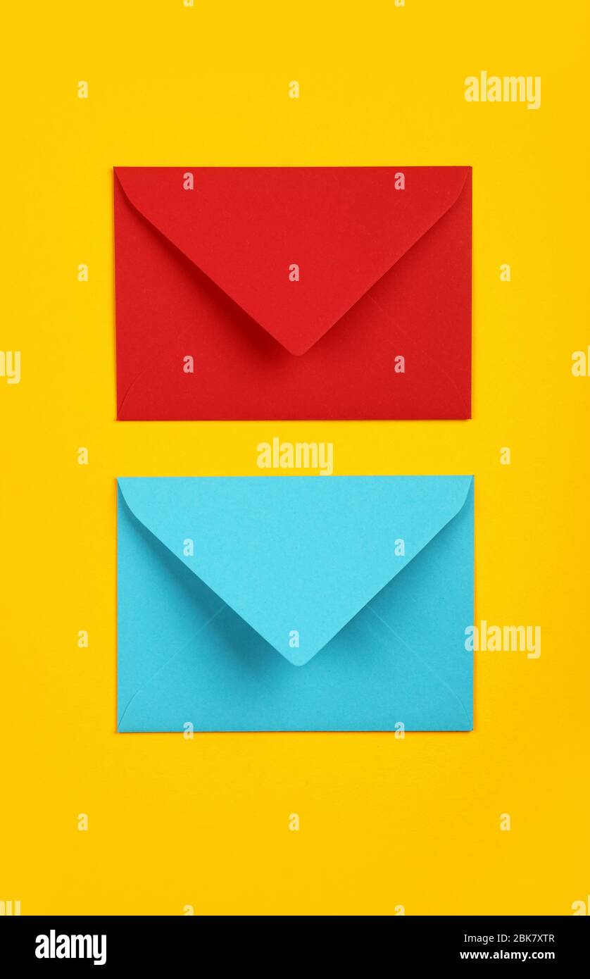 Two closed blank pastel blue and red paper envelopes over vivid yellow ...