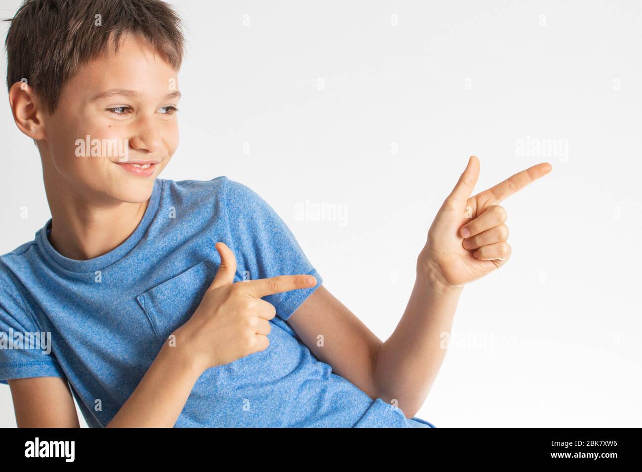Adorable boy pointing with index fingers at something on white ...