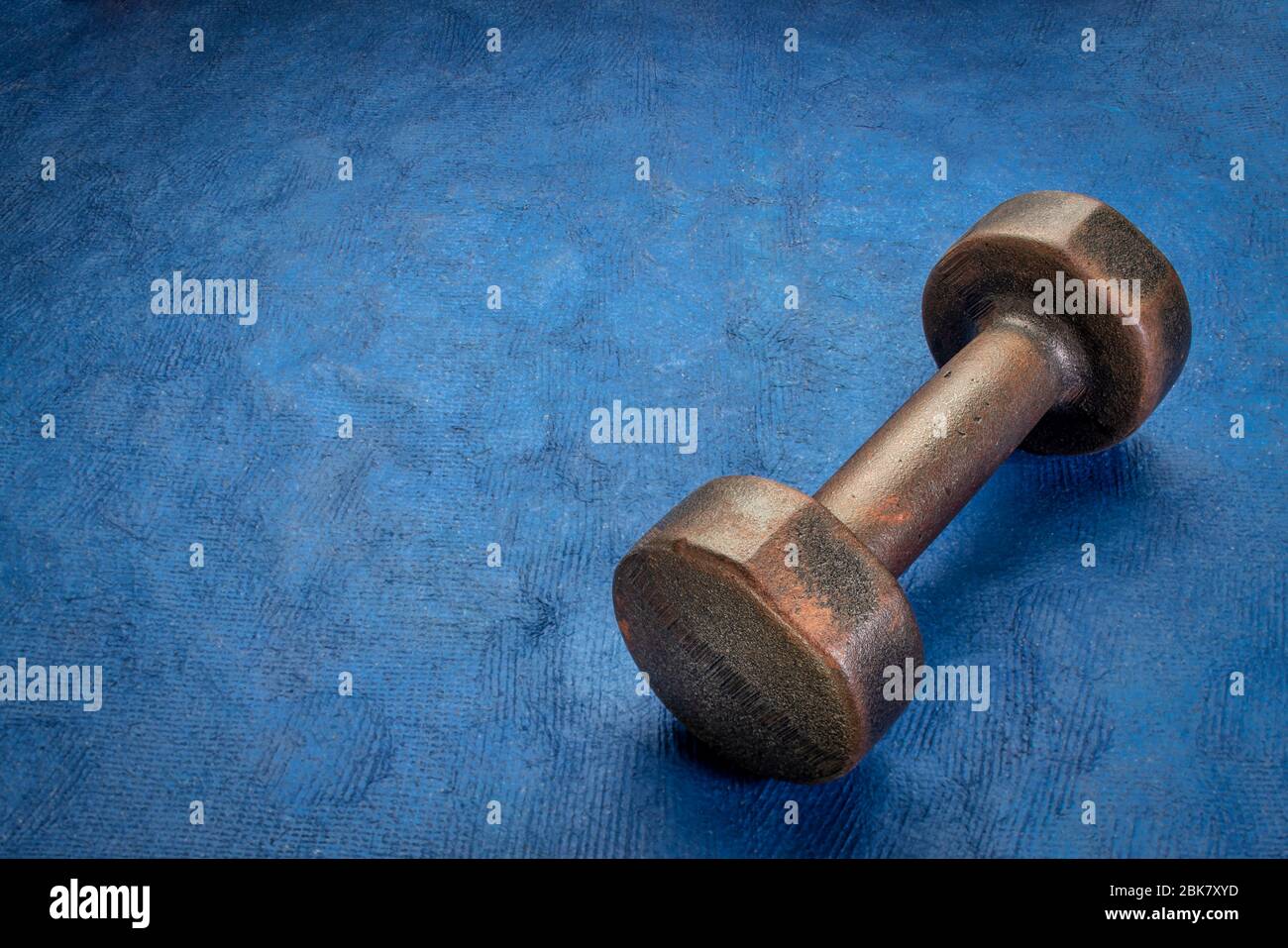 old rusty dumbbell on textured handmade bark paper with a copy space ...