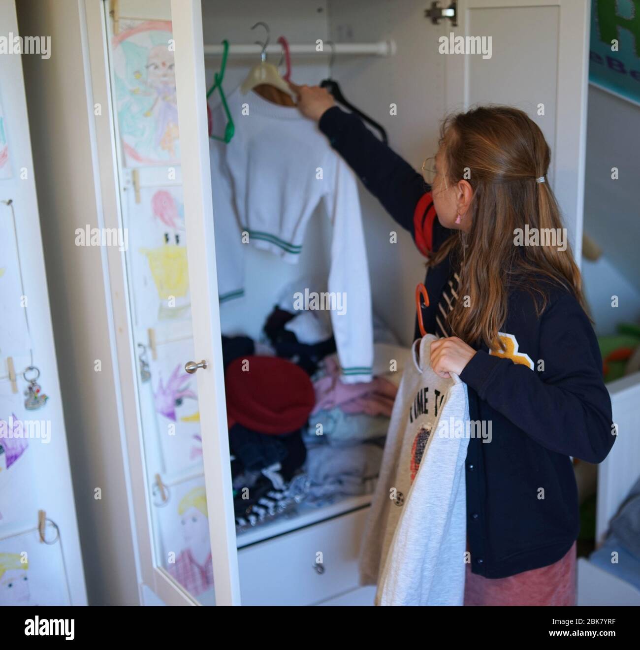 Young girl choosing her clothes from the closet. Kid thinking what to ...