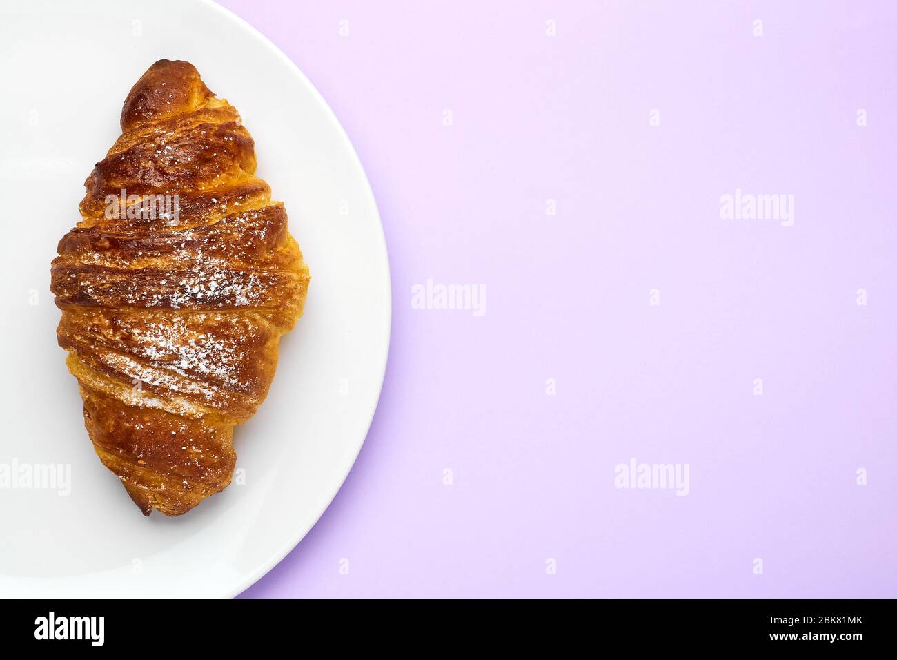 Freshly baked french croissants on a white plate on the purple ...