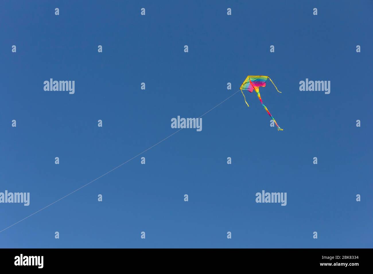 Colorful ribbons and kite figures hanging on poles and flying on blue ...