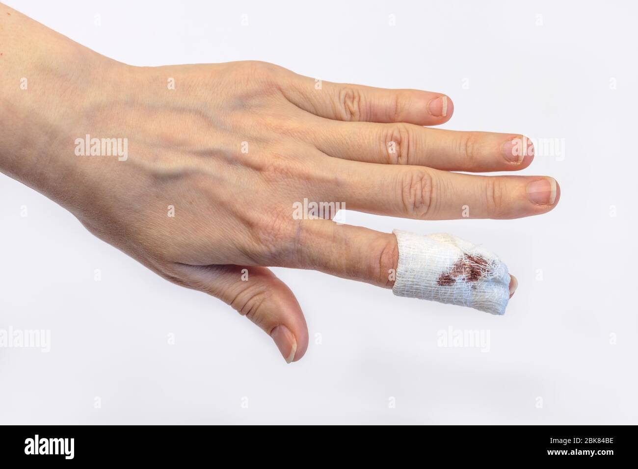 a left injured woman's hand with a bandaged index finger on a white ...