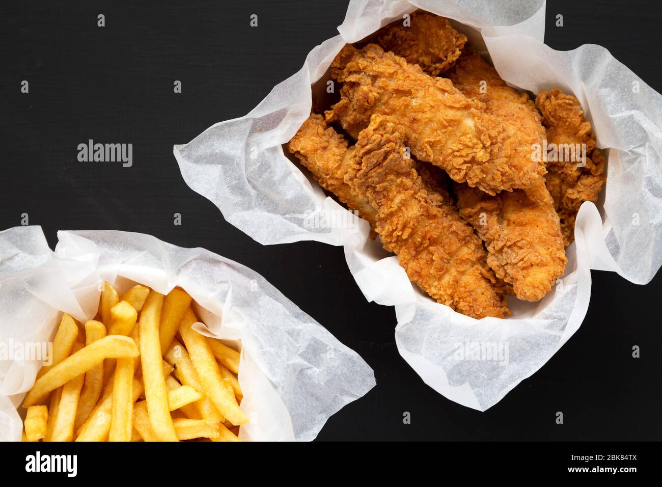 Fried Chicken Strips and French Fries on a black surface, top view ...