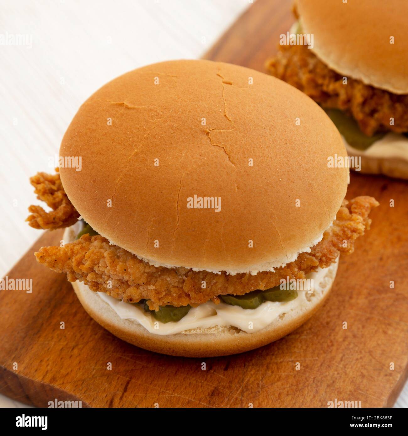Homemade Burgers with fried chicken strips on a rustic wooden board ...