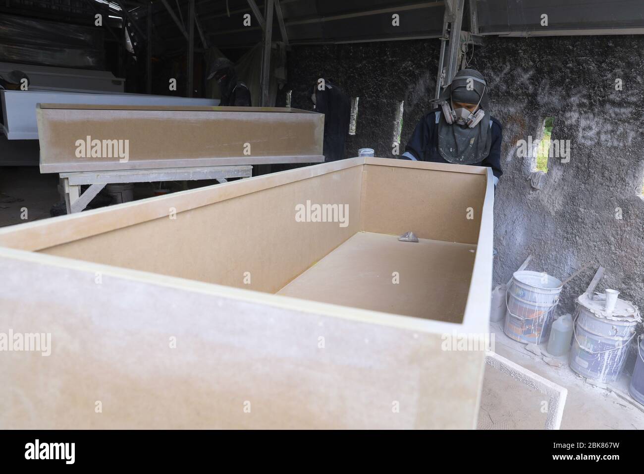 A coffin maker working on special coffins coated with plastic to ...