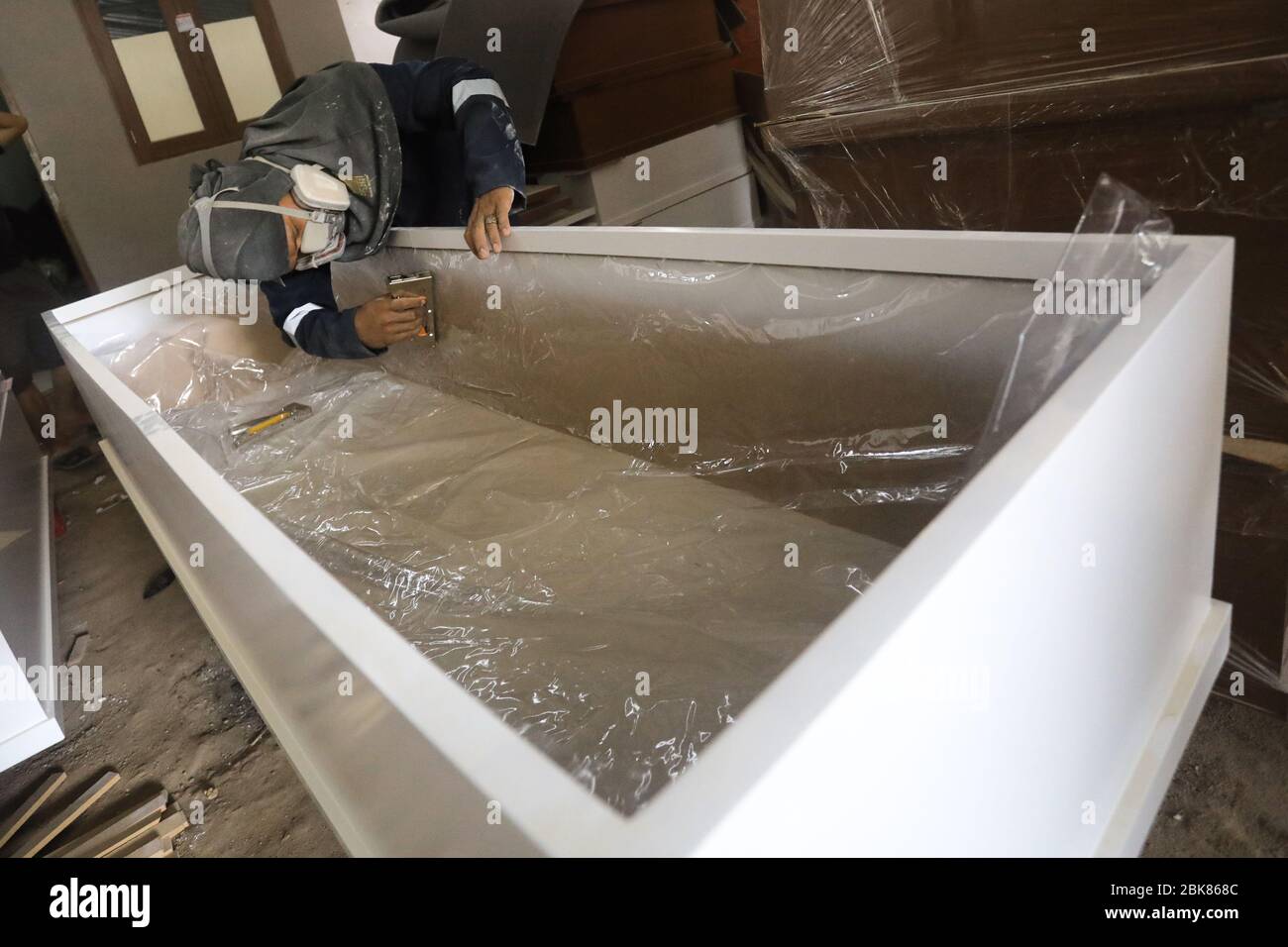 A coffin maker working on special coffins coated with plastic to ...