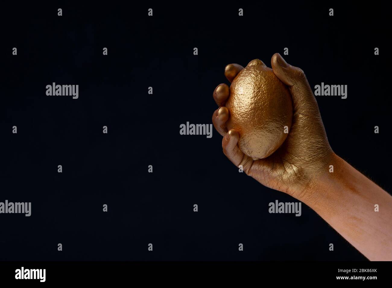 Minimalism concept. Hand holds lemon in gold paint Stock Photo - Alamy