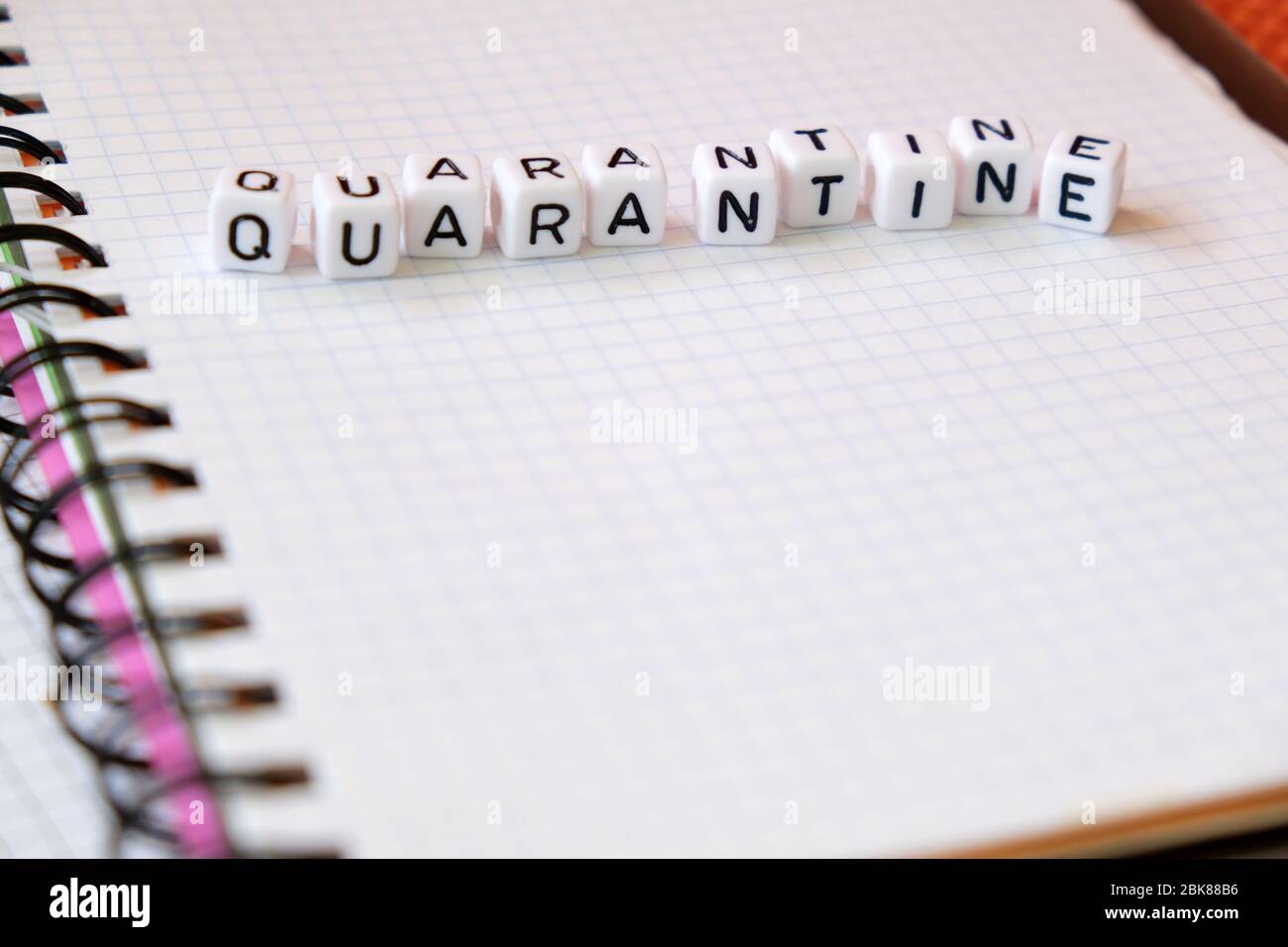 Text "Quarantine", word made of cubic letters on a white paper note pad ...