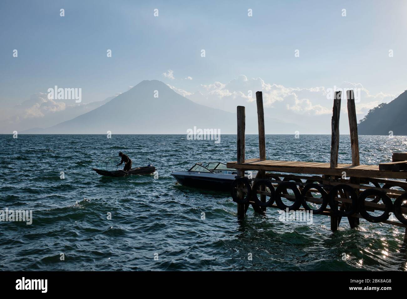 Fisherman in a small boat fishing in Lake Atitlan with views of Atitlan ...