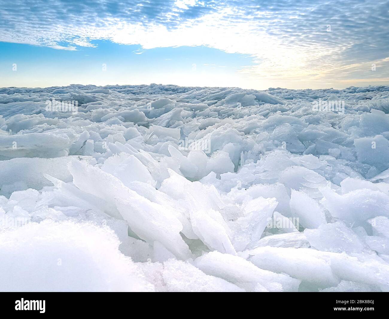 Winter costal landscape with frozen sea, blue sky and beautiful fleecy ...