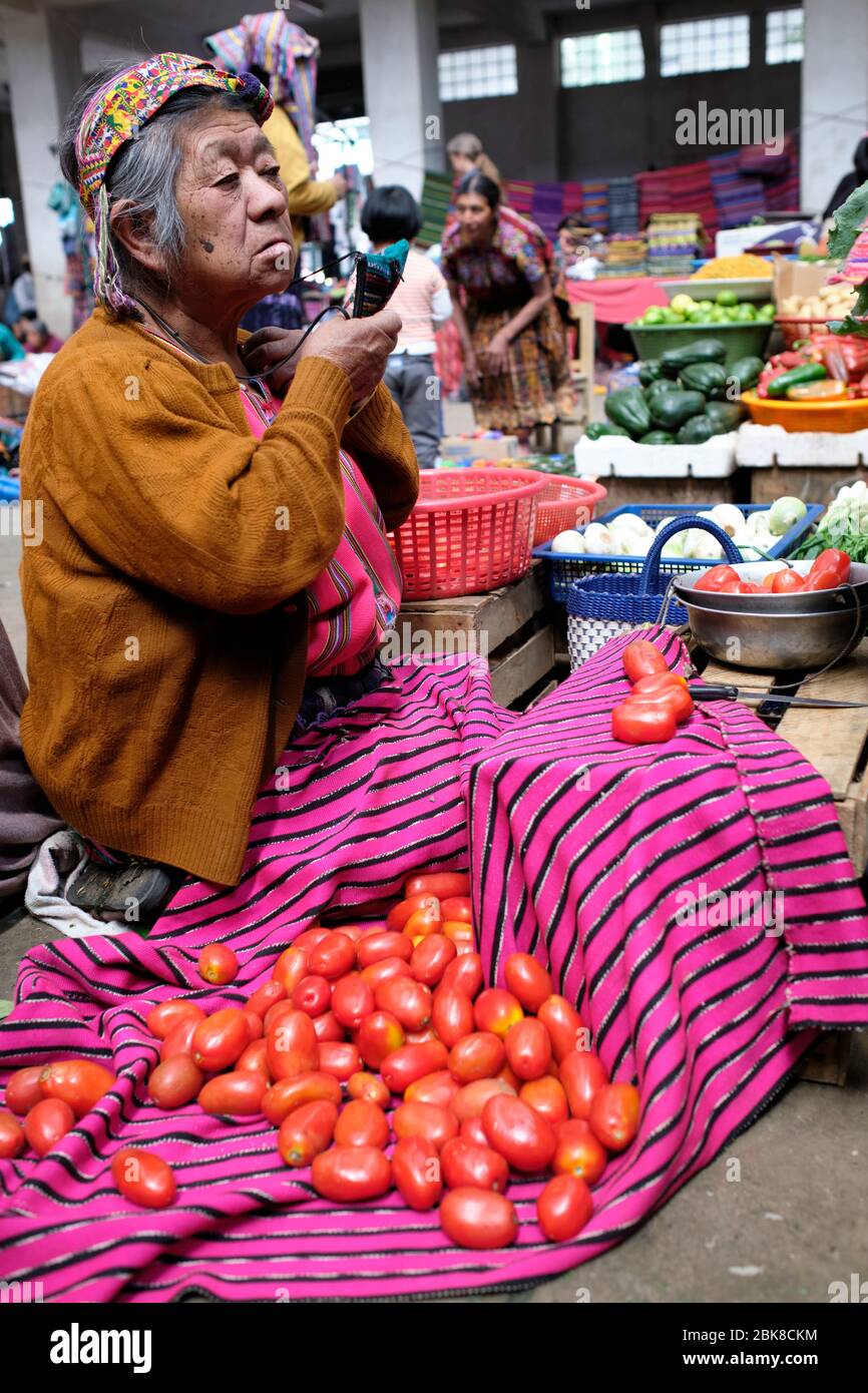 Woman dressed with indigenous colourful outfit selling tomatoes in a ...