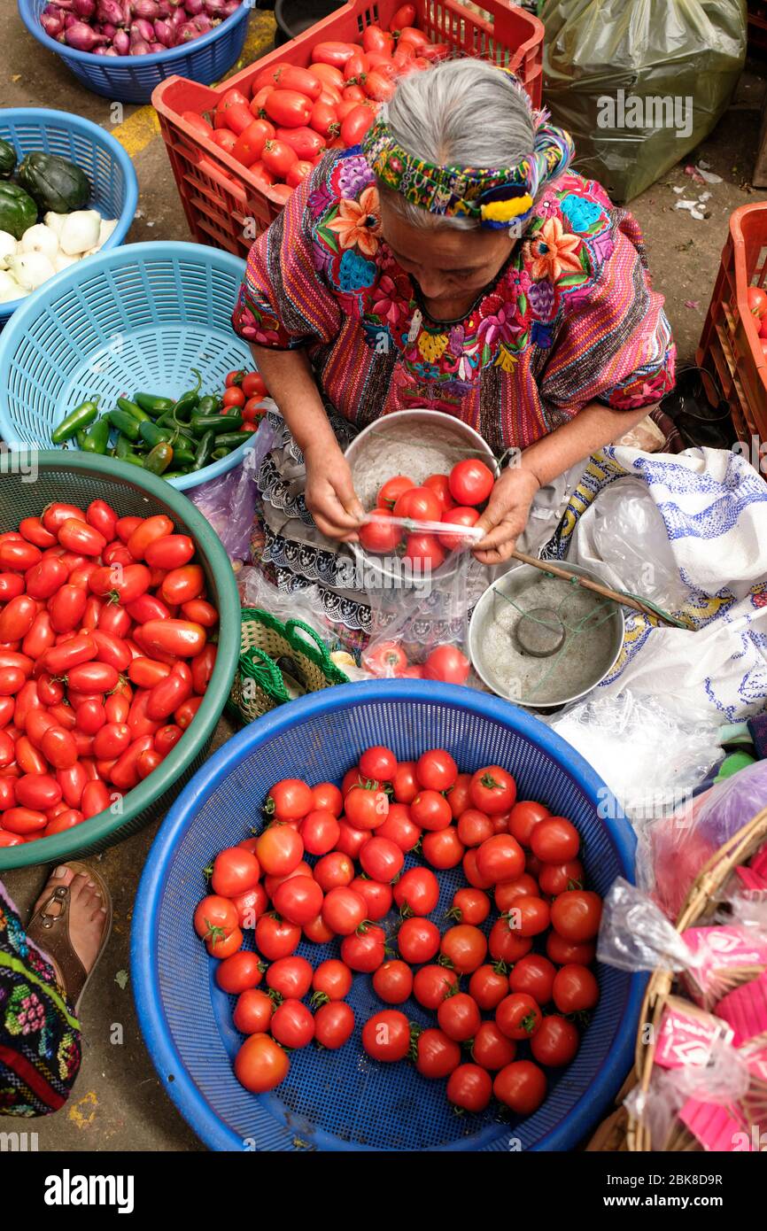 Woman dressed with indigenous colourful outfit selling tomatoes in a ...