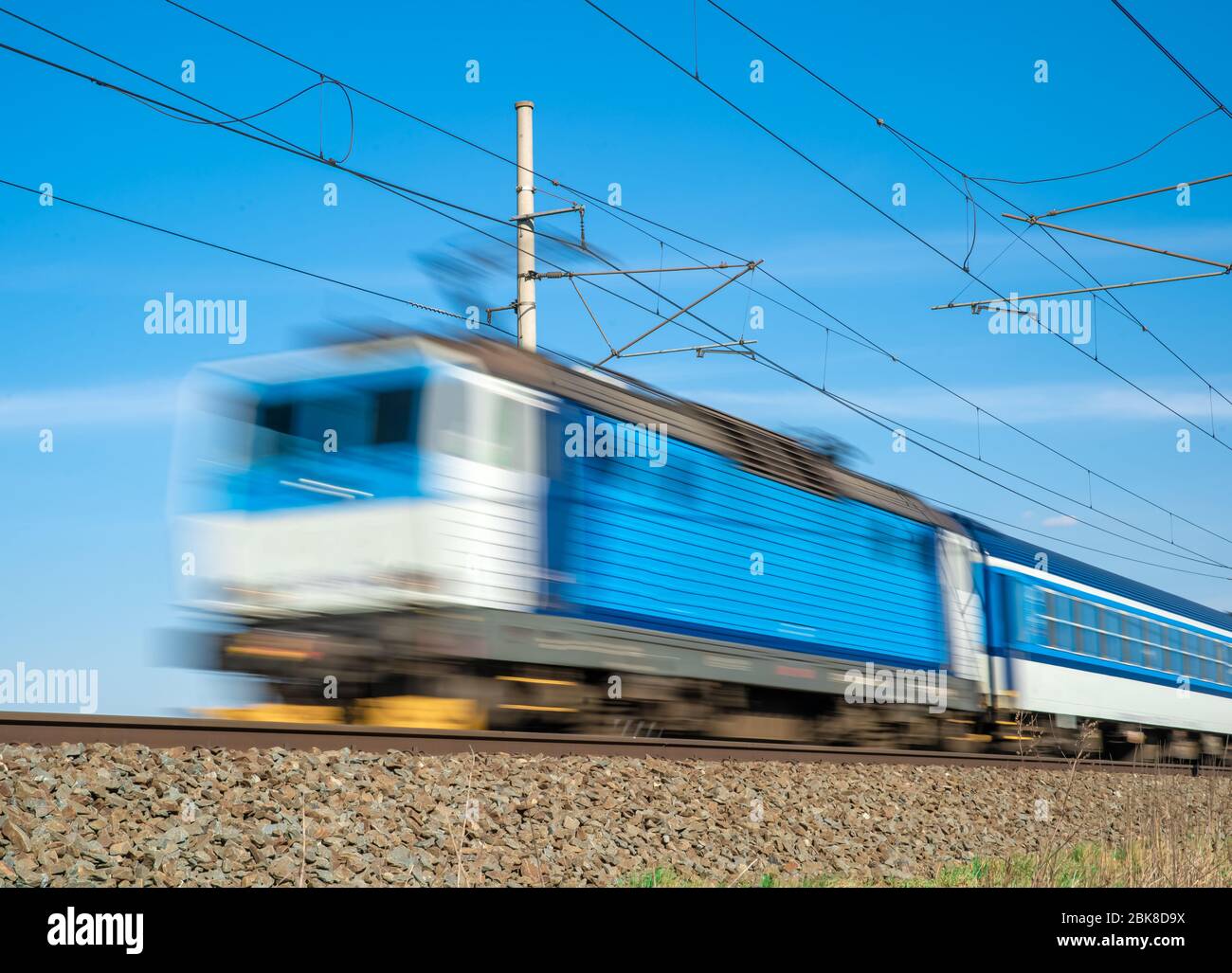 Blue train powered by electricity, drives through the countryside ...