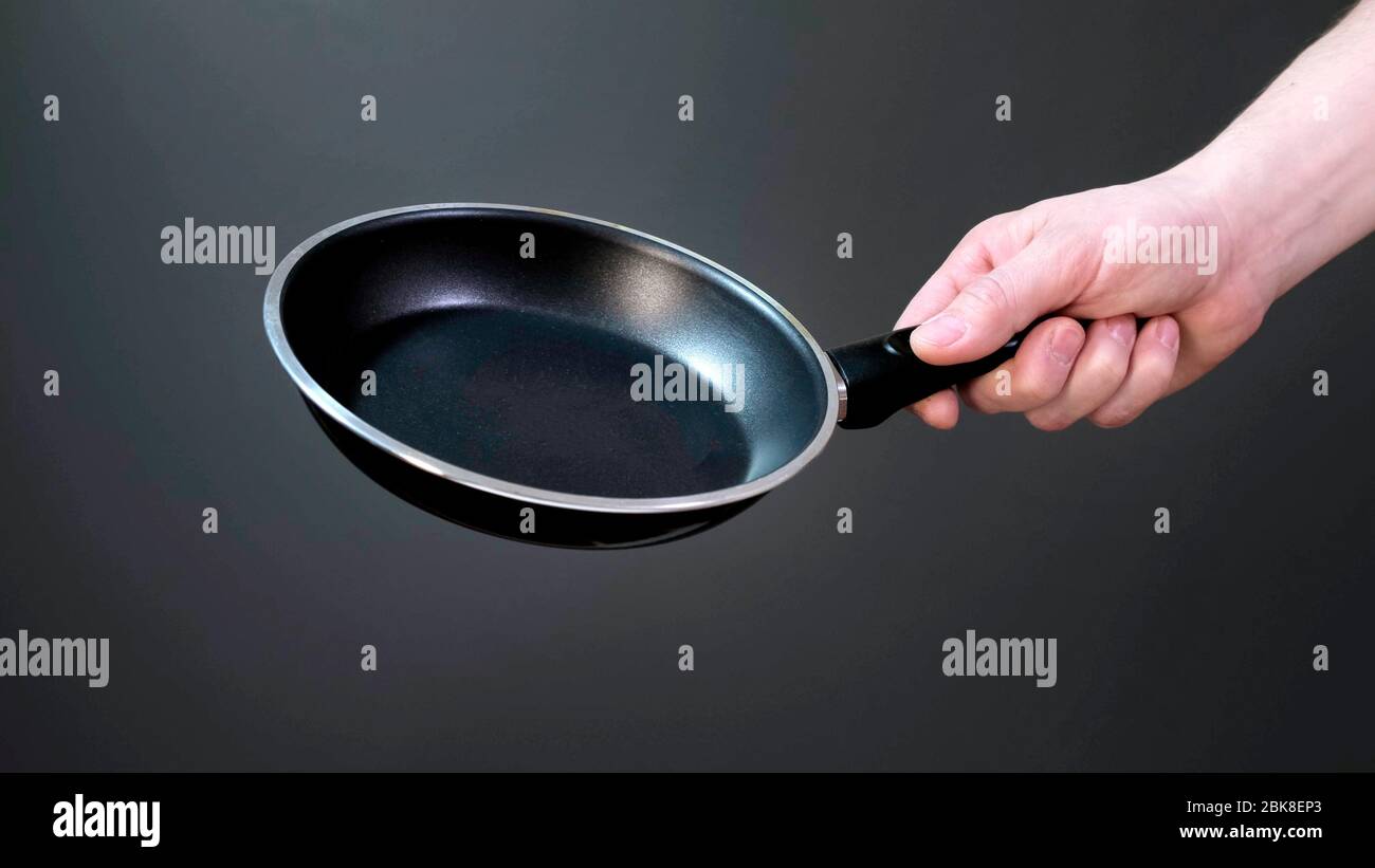 Hands holding new empty black frying pan. Close up Stock Photo - Alamy