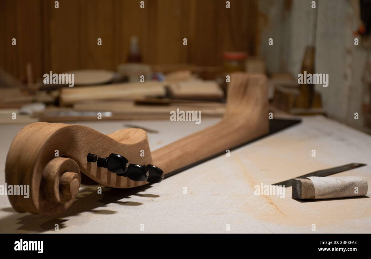 a scene of luthier workshop workbench with a cello neck, headstock ...