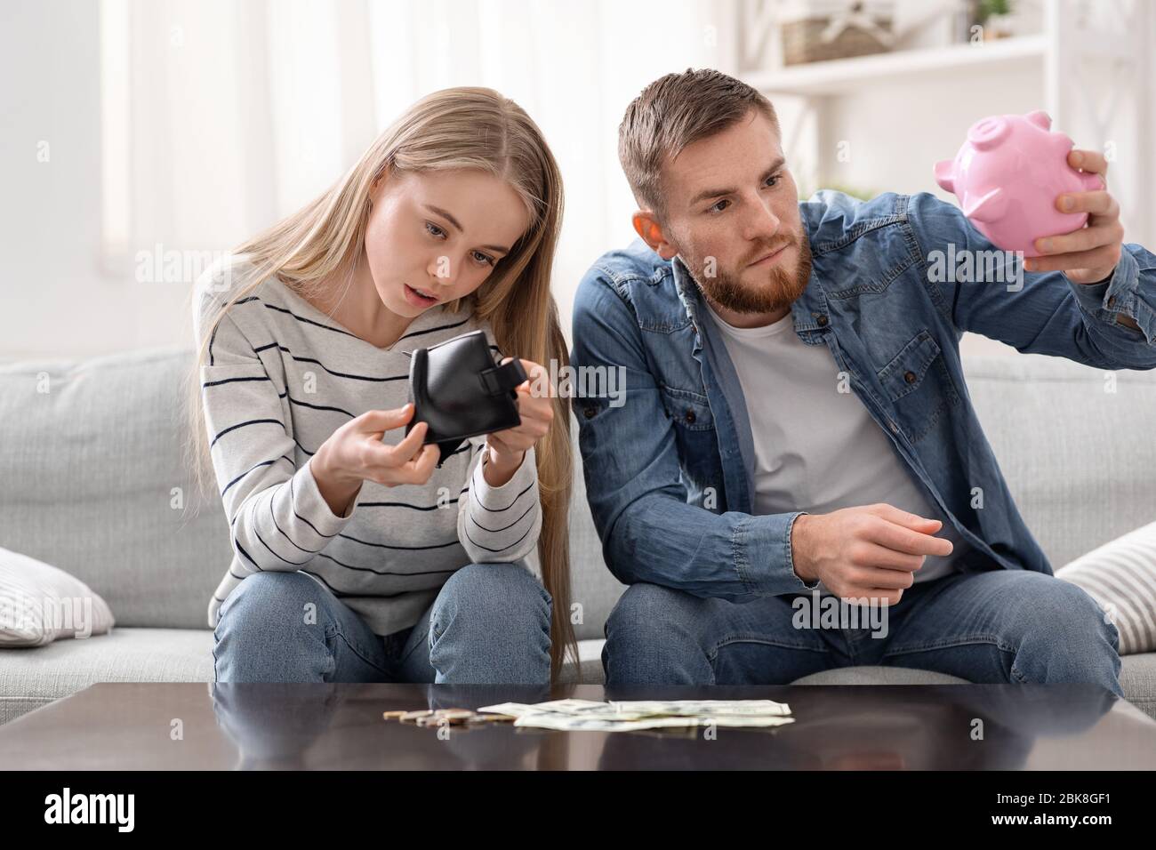 Desperate couple looking for money in wallet and piggybank Stock Photo ...