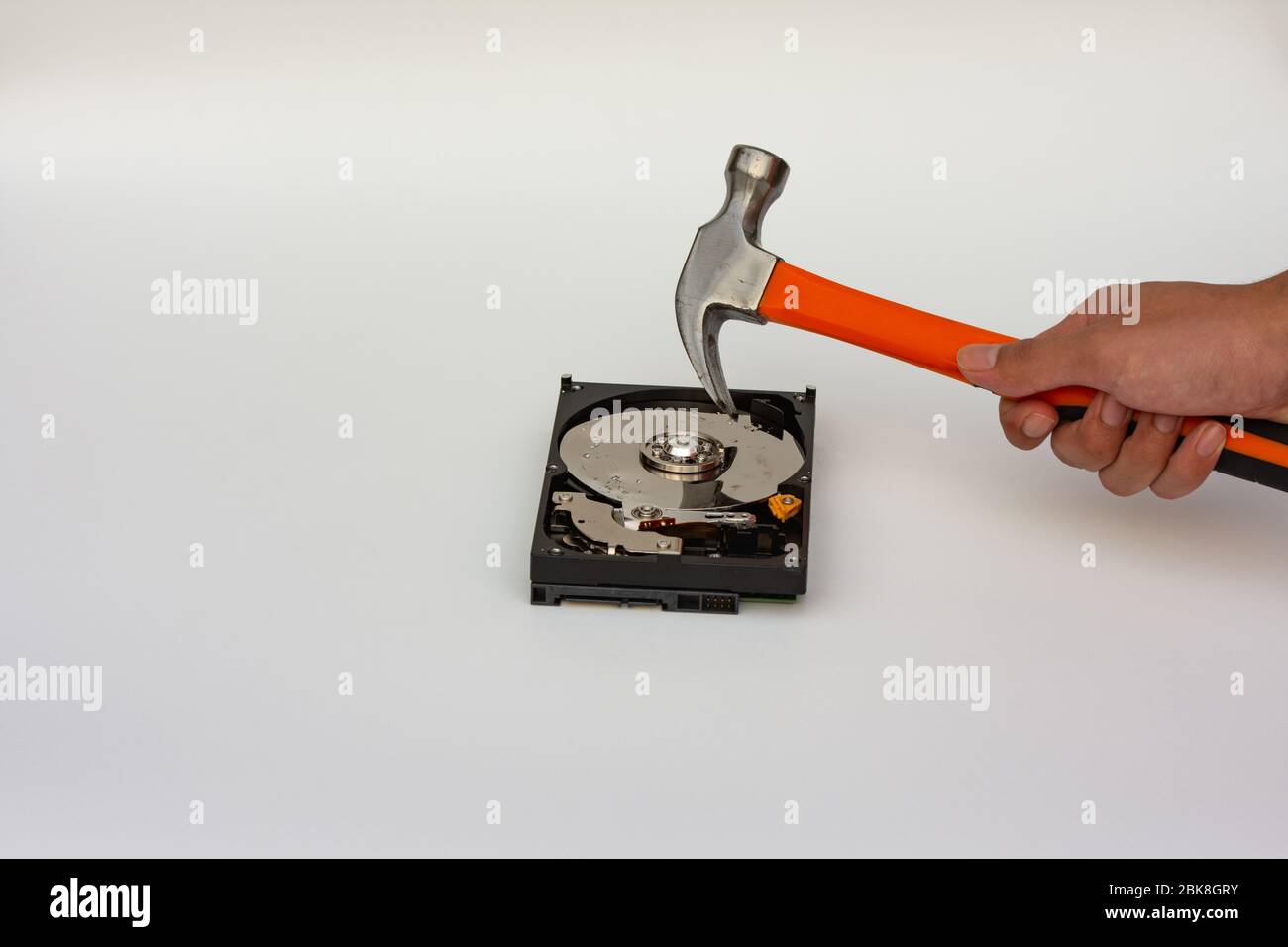 Hard disk drive platter being destroyed with a hammer on a white ...