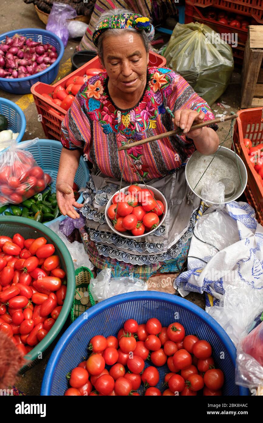 Woman dressed with indigenous colourful outfit selling tomatoes in a ...