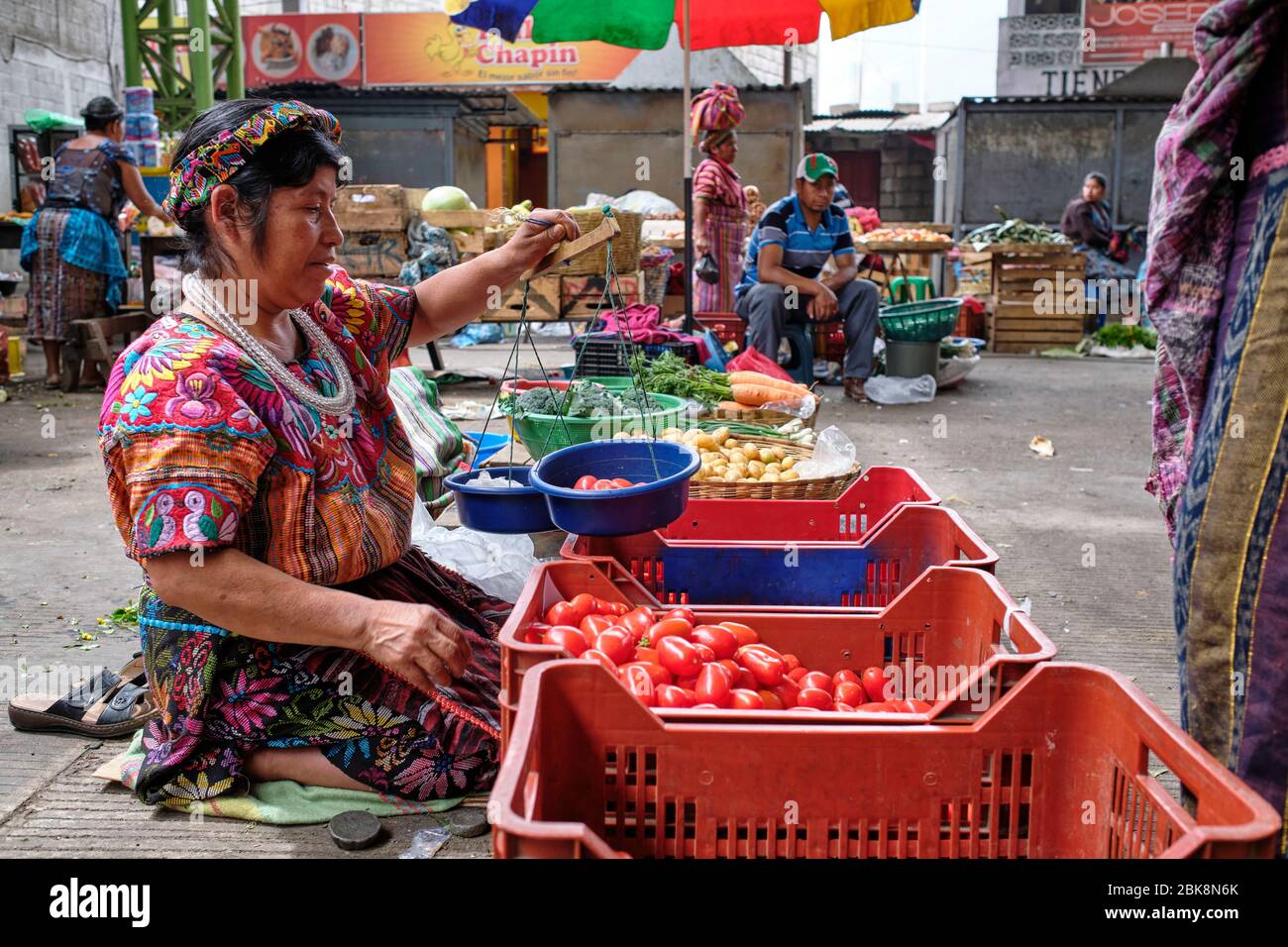 Woman dressed with indigenous colourful outfit selling tomatoes in a ...