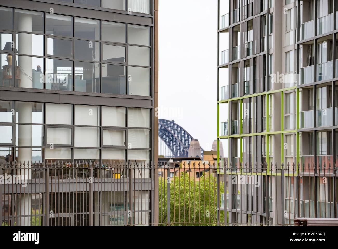 Glimpses of the Sydney Harbour Bridge appear between two tall apartment ...