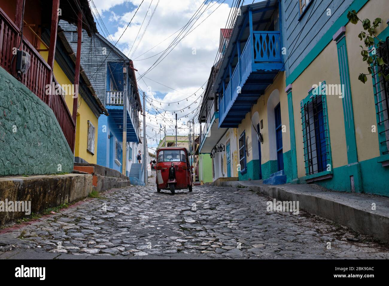 Red rickshaw driving on the cobbled streets in the old area of Flores ...