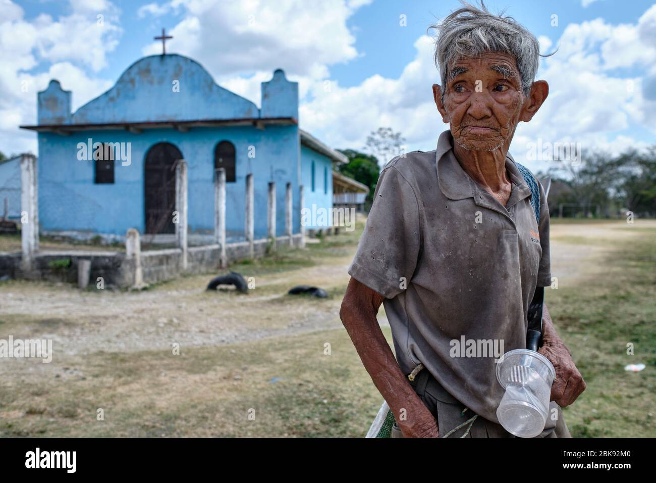 Portrait of an old peasant in front of the colonial church of Carmelita ...