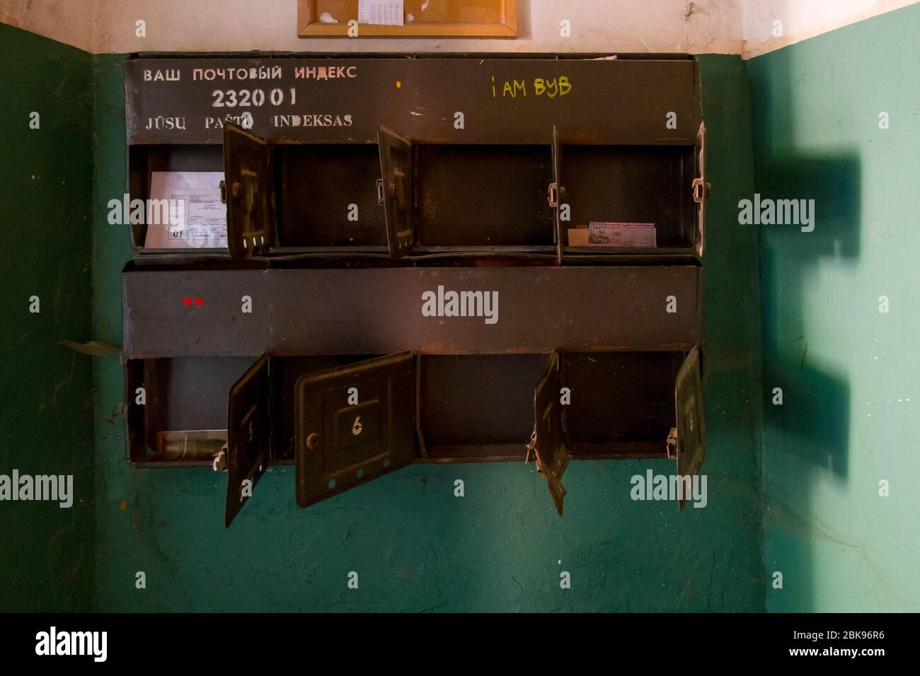 An old, beat up, worn set of metal mailboxes mounted on a wall in a ...