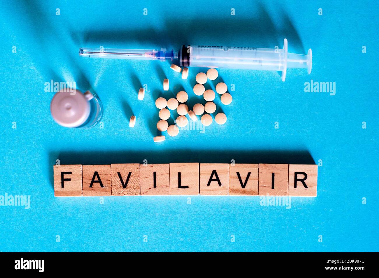 shot of tablets, glass bottle, syringe on blue and wooden blocks with ...