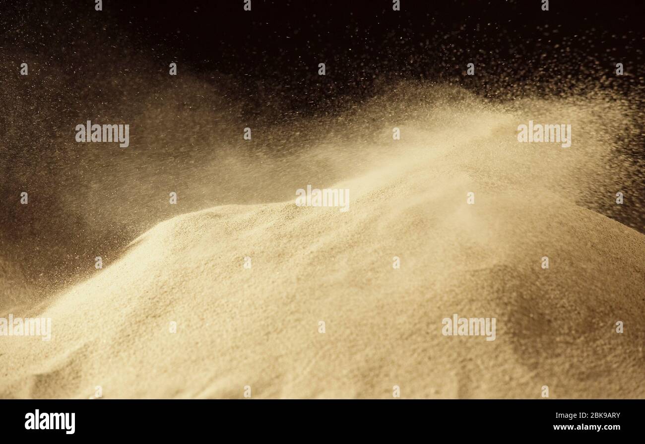 Gold sand splash against on dark background Stock Photo - Alamy