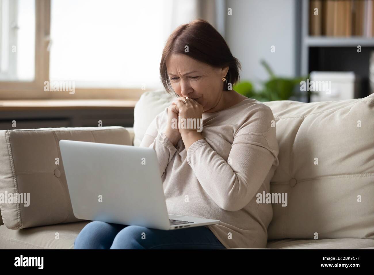 Sad mature woman looking at laptop screen and crying Stock Photo - Alamy