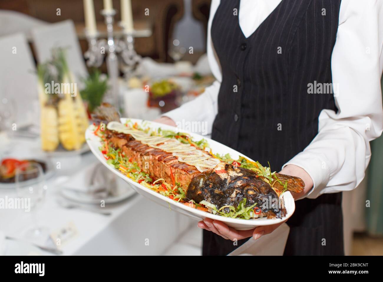 waitress in a white blouse and a black uniform holding a white plate ...