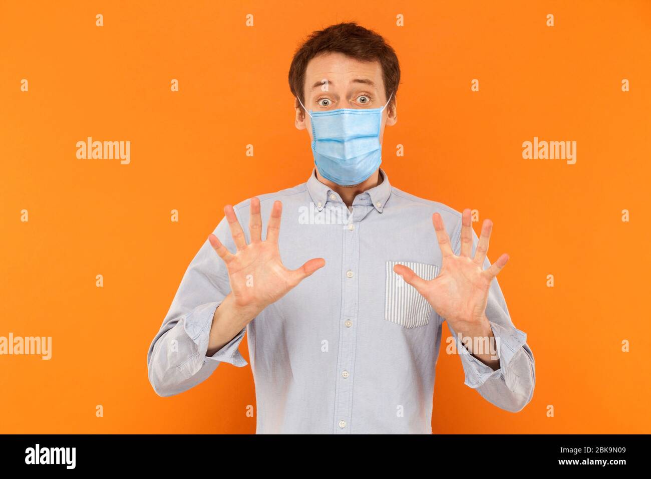 Portrait of scared young worker man with surgical medical mask standing ...