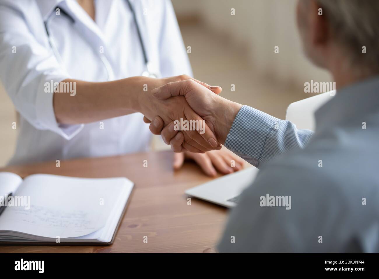 Female doctor and senior patient shake hands, close up view Stock Photo ...