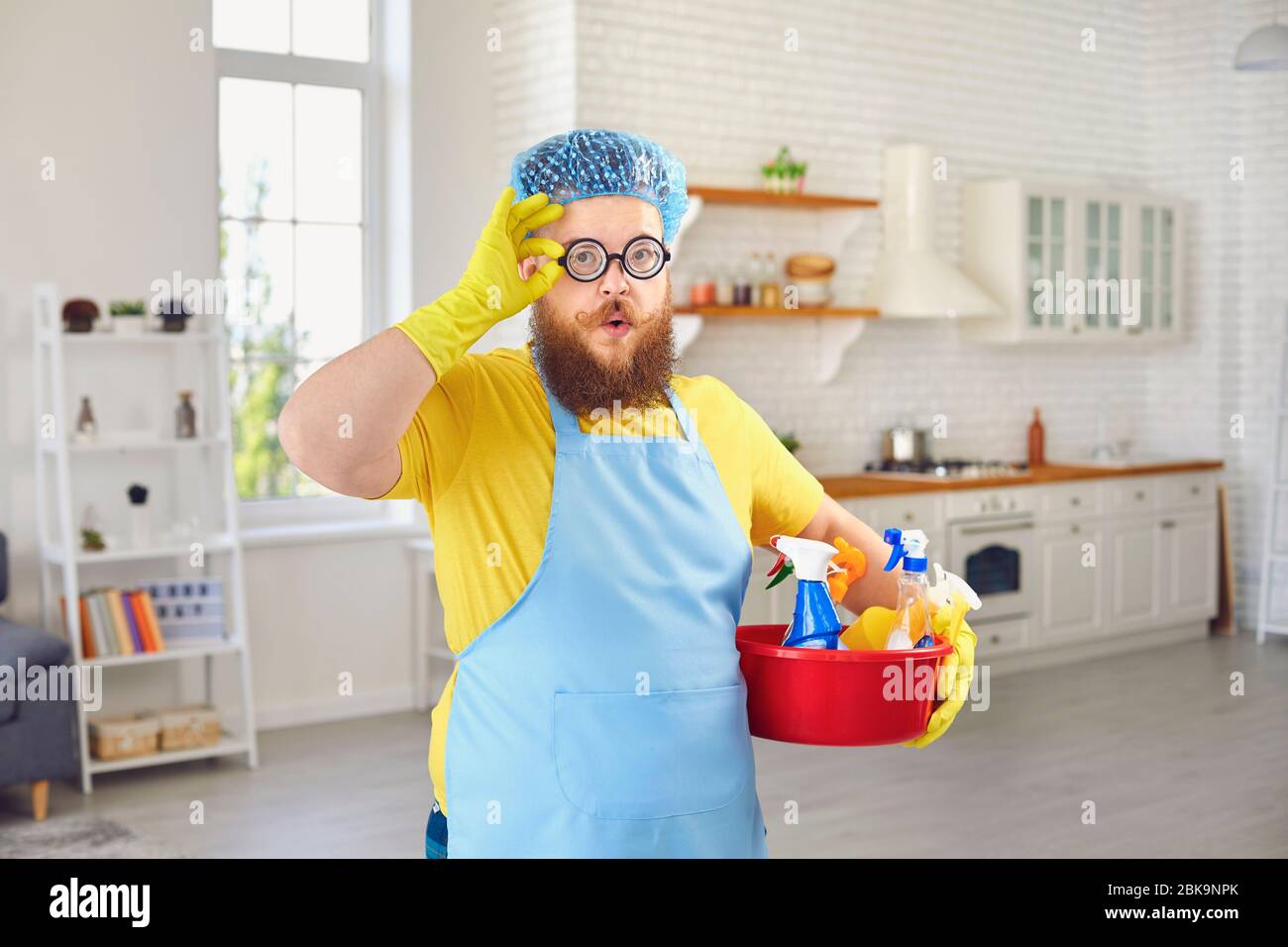 Funny fat man in an apron and yellow cleaning gloves is cleaning in the ...