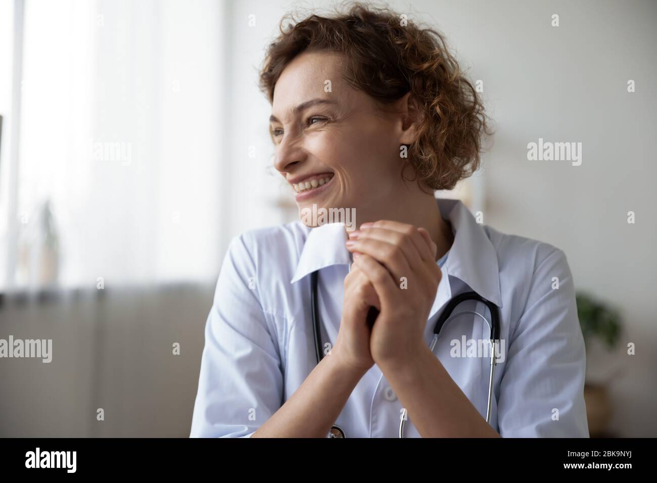 Cheerful young adult female professional doctor laughing looking away ...