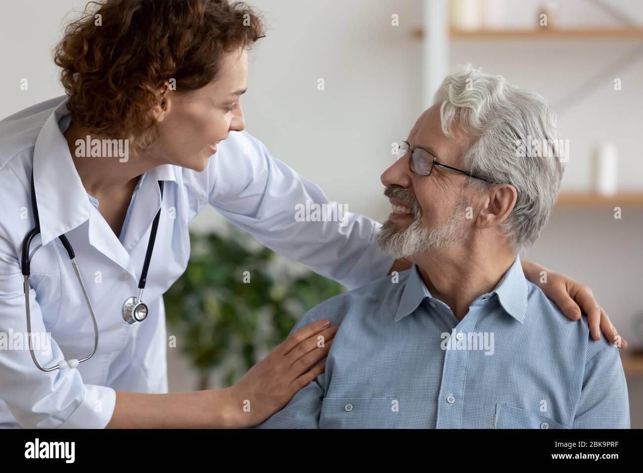 Caring female doctor embracing helping happy senior male patient Stock ...