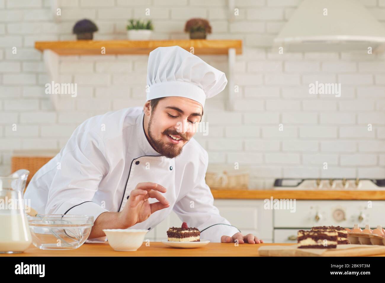 A male pastry chef works decorating a cake on a kitchen bakery Stock ...