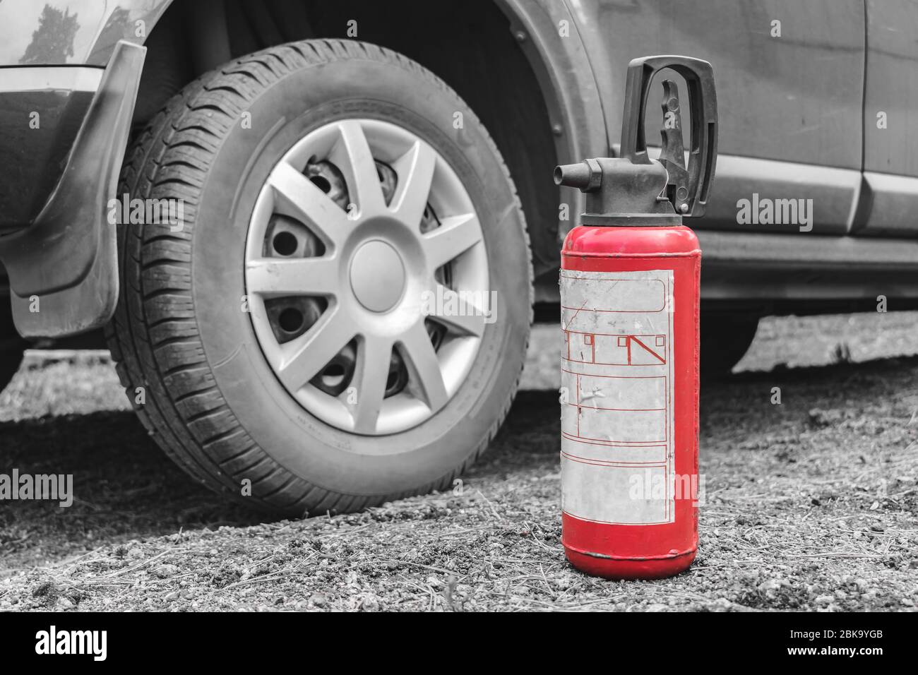 A fire extinguisher stands on the ground near the car as fire safety ...