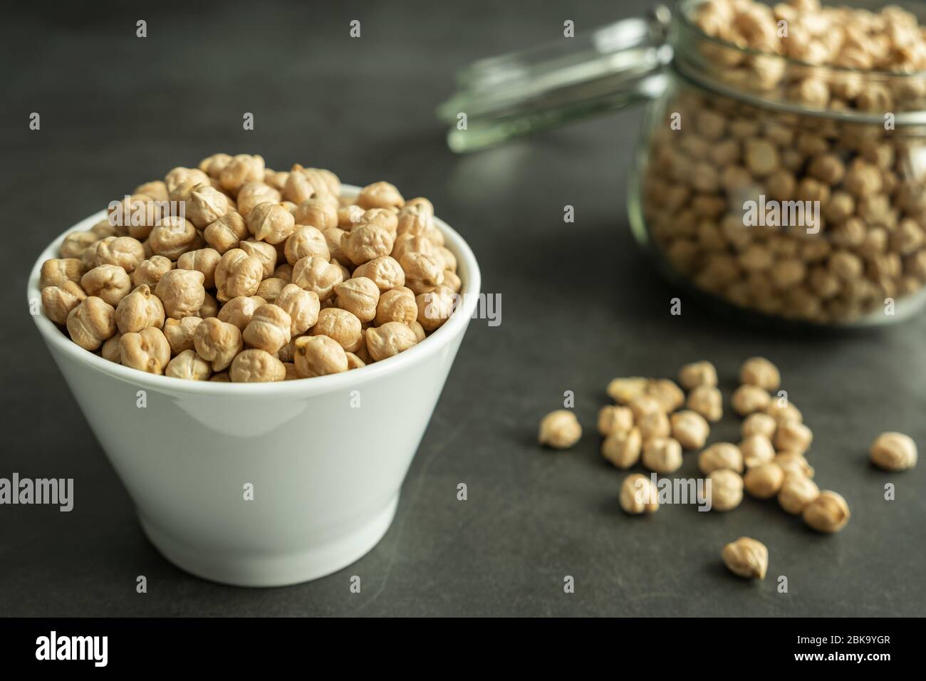 Raw chickpea in white porcelain bowl on stone, concrete background ...